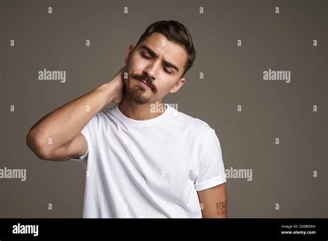 Image Of Tired Handsome Guy Rubbing His Neck While Posing On Camera