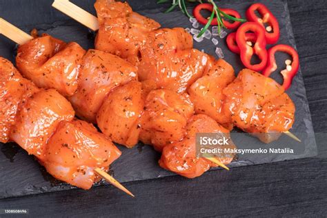 검은 접시와 나무 테이블에 향신료와 양념장에 생 닭 꼬치 원시 절인 매운 치킨 꼬치 닭 고기가 닫힙니다 마리네이드에 생 고기
