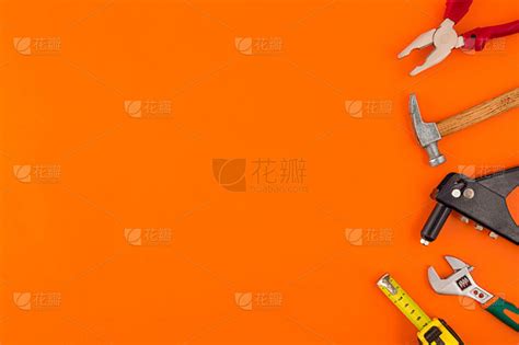 向导的工作工具。卷尺，螺丝刀，锤子，扳手，夹子，螺丝，钻头和其他工具在一个橙色的表面。