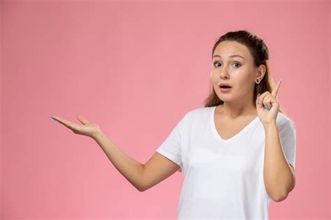 Вид спереди молодая привлекательная женщина в белой футболке позирует с поднятой рукой и