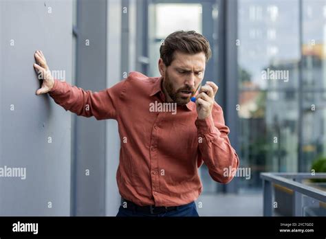Man Wearing Smart Casual Shirt Using Inhaler For Asthma Outdoors Representing Respiratory