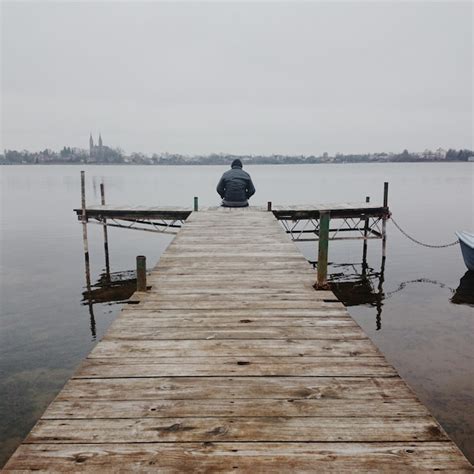 Premium Photo Person Sitting On Jetty In Front Of Sea Against Clear Sky