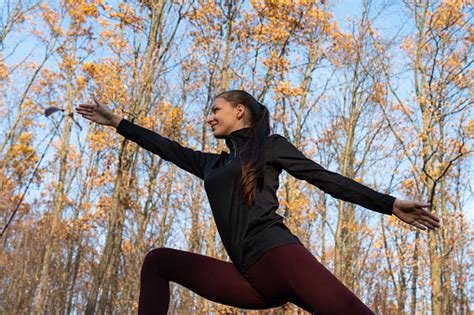 노란 잎 건강한 생활 개념과 가을 숲 중 아사나 요가 운동을 연습 스포츠웨어에서 젊은 슬림 핏 갈색 머리 소녀 Track And Field Event에 대한 스톡 사진 및