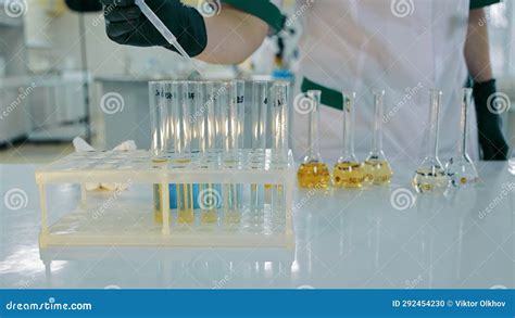 A Laboratory Technician Drips A Chemical Solution Into A Test Tube A