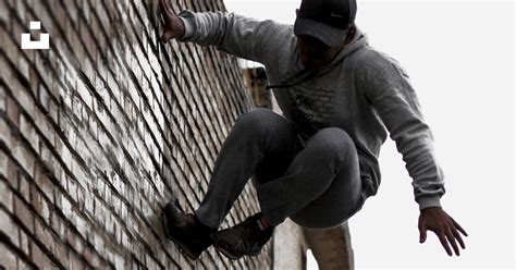 회색 재킷과 검은 바지를 입은 남자가 낮에 갈색 벽돌 벽에 앉아 있다 사진 Unsplash의 무료 마슈하드 이미지