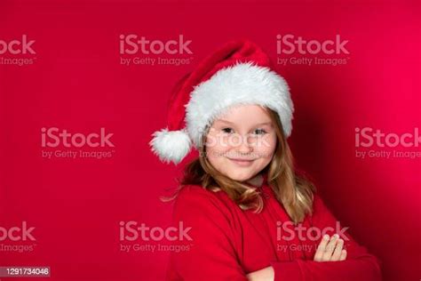 예쁜 어린 여학생 산타 클로스 모자와 빨간 스웨터 앞 의 빨간 배경 12월에 대한 스톡 사진 및 기타 이미지 12월 개념 겨울 Istock