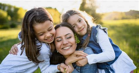 두 명의 어린 딸과 함께 봄 자연 속에서 야외에서 즐거운 시간을 보내고 포옹하는 어머니의 전면 모습 사진 Unsplash의 사진술 이미지