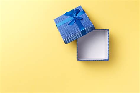 노란색 배경에 파란색 리본 파란색 빈 선물 상자입니다 맨 위 보기 플랫 레이 공간을 복사합니다 다채로운 배경 최소한의 크리스마스 새해 창조적 인 개념 트렌디한 파스텔 칼라