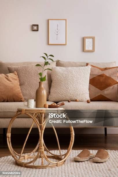 V베개 격자 무늬 커피 테이블 및 개인 액세서리가있는 베이지 색 소파가있는 거실 인테리어의 세련된 구성 포스터를 모의 붙인 베이지색 벽 가정 장식 템플렛 거실에 대한 스톡