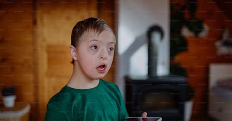 다운 증후군을 앓고있는 어린 소년은 바닥에 앉아 집에서 스마트 폰을 사용합니다 사진 Unsplash의 마루 이미지