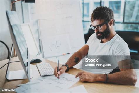 동료 전문가 눈 안경을 착용 현대 로프트 스튜디오데스크톱 컴퓨터와 사무실에서 일하고 수염 화이트 빈 화면을 표시 합니다 흐리게 배경입니다 수평 건축가에 대한 스톡 사진 및