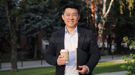 Portrait Of Adult Korean Businessman Holding Coffee And Documents While