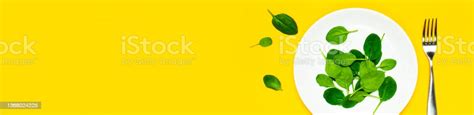 밝은 노란색 배경 플랫 평지 상단 보기 복사 공간에 흰색 접시 포크에 신선한 녹색 시금치 잎 아기 젊은 시금치 잎 건강 한 음식 다이어트 창조적 인 음식 개념 0명에 대한