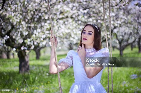 젊은 아름 다운 소녀는 봄에 사과 과수원에서 임시 그네에 앉아 있다 모델의 완벽 한 그림에 흰색 레이스 드레스 사진 세션을 엽니다 귀여운에 대한 스톡 사진 및 기타 이미지