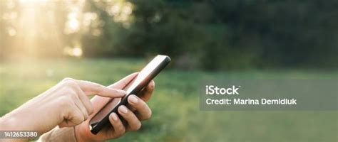 스마트 폰을 이용한 여성 손의 클로즈업 자연 배경 야외에서 일몰에 휴대 전화를 사용하는 여성 스마트 폰 화면을 만지는 인식 할 수없는 사람 밖에서 핸드폰을 들고 있는 알 수