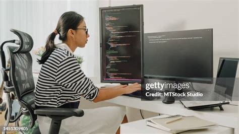Young Asian Woman Software Developers Using Computer To Write Code Sitting At Desk With Multiple
