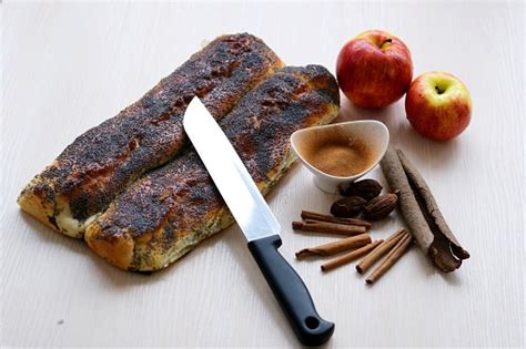 크리스마스 양귀비 씨앗 케이크 얇게 썬 양귀비 씨앗 케이크 전통적인 크리스마스 케이크 계피와 육두구 계피 스틱 흰색 배경의 나무 도마에 향기로운 향신료 12월에 대한 스톡