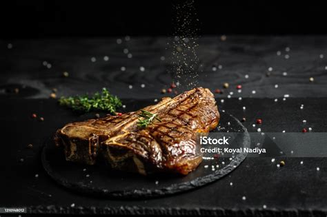 바베큐 숙성 와규 포터 하우스 스테이크 슬레이트 보드에 상단 보기로 슬라이스 검은 테이블에 향신료와 쇠고기 T뼈 육즙 스테이크