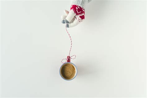 빨간 흰색 끈에 매달려 커피 한 잔으로 만든 풍선 공기 비행 풍선 니트 장갑에 여자 손 또는 활에 묶여 꼬기 흰색 테이블입니다