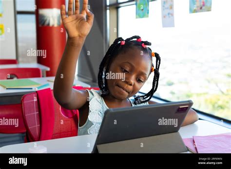 Happy African American Schoolgirl Having Tablet Video Call In Classroom At Elementary School