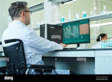 Mature Male Scientist With Disability Typing On Computer Keyboard While