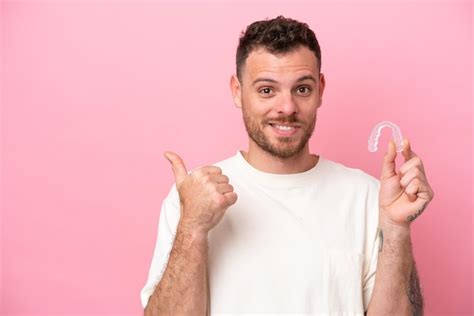 Premium Photo Brazilian Man Holding Invisible Braces Pointing To The Side To Present A Product