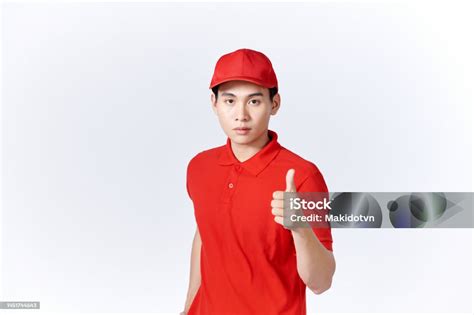 빨간 모자 티셔츠 유니폼 작업복을 입은 전문 배달원 직원 남자는 고립된 제스처처럼 엄지손가락을 치켜드는 딜러 택배로 일합니다