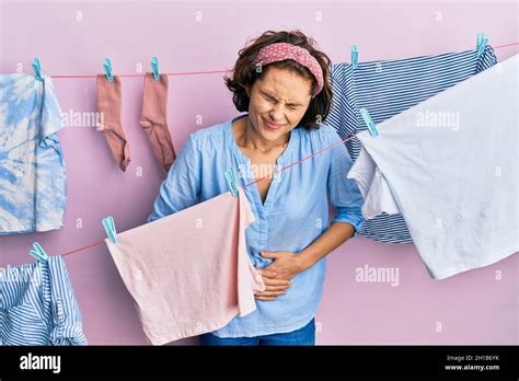 Young Brunette Woman Doing Laundry Around String Hangs With Hand On