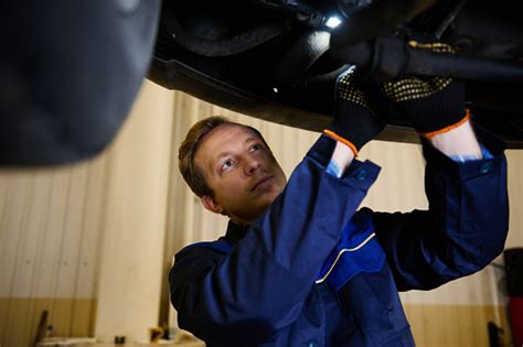 수리 서비스에서 자동차 정비사 마스터 작업장에서 차량 리프트에 자동차 아래 상태를 확인하는 기술자 램프를 사용하여 섀시를 확인하는 자동차의 정렬을 확인하는 정비사 개선에