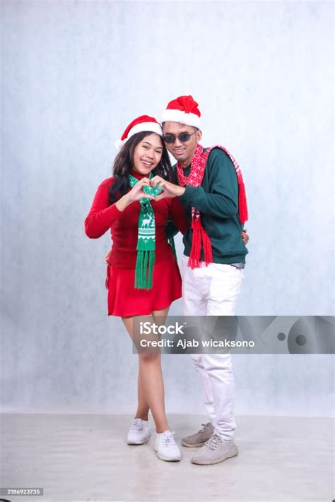 크리스마스와 새해를 축하하는 산타 모자와 함께 파티 옷을 입은 전신 아시아 커플 손은 사랑 애정을 행복하게 서명합니다 흰색 배경에 고립되어 있습니다 20 24세에 대한 스톡