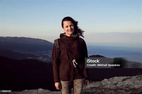 여자 자 켓에서과 배낭은 태양 광선에 바다가 내려다 보이는 산 위에 서 있다 20 29세에 대한 스톡 사진 및 기타 이미지 20 29세 경관 관광객 Istock