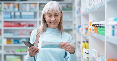 성숙하고 행복한 여성과 약국의 선반에서 약물 치료 또는 구호를위한 전화가있는 상자 약국에서 의약품 건강 관리 또는 의료 약물에 대한 미소를 가진 노인 여성 또는 고객 65