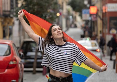 A Transgender Woman Holding A Rainbow Flag In A City Street The Flag