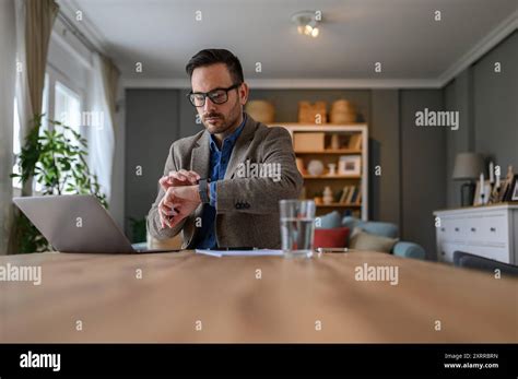 Portrait Of Serious Businessman Checking Time On Wristwatch While