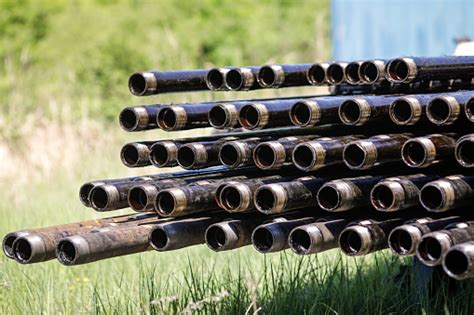 석유 굴착 드릴 파이프는 배경에 석유 산업 노동자와 함께 쌓여있다 석유 및 가스 산업 유전에 원유 펌프 잭 석유 및 가스 우물의 드릴링 0명에 대한 스톡 사진 및 기타