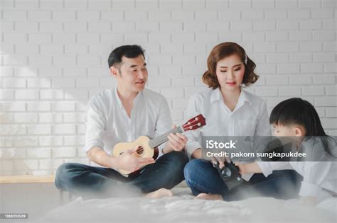 아시아 일본 가족 아버지 어머니 아들 흰색 셔츠를 입고 카메라를 들고 기타 아큘레 화이트 룸 하우스에서 흰색 침실에 사진 포즈 아들의 추억의 귀여움을 유지 하려면 닌 어린