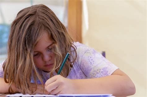 Young Girl Drawing With A Pencil On Paper Focusing Intently On Her