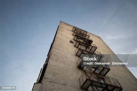 고층 건물에는 밝은 푸른 하늘과 대조를 이루는 눈에 띄는 화재 대피 계단이 있습니다 오후 조명은 구조물의 세부 사항을 향상시킵니다 0명에 대한 스톡 사진 및 기타 이미지