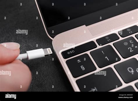 Woman Plugging Usb Cable With Lightning Connector Into Laptop Port On Dark Table Closeup Stock