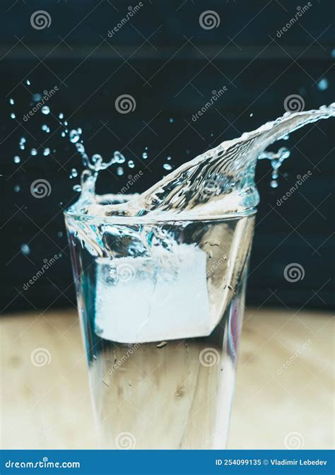 An Ice Cube Falls Into A Glass Of Clean Drinking Water Splashing It