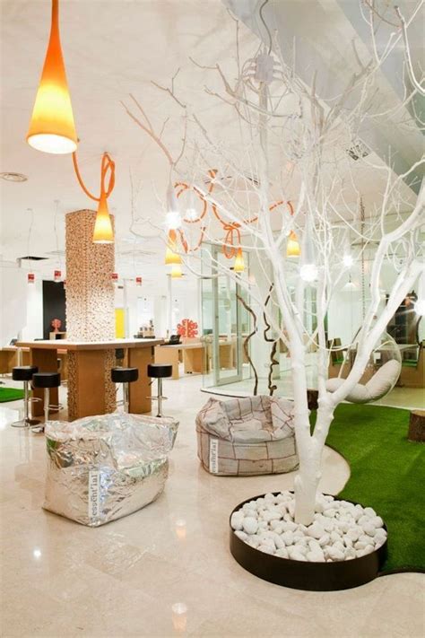 An Office Lobby Decorated With Artificial Trees And Fake Rocks In The Center Along With Green