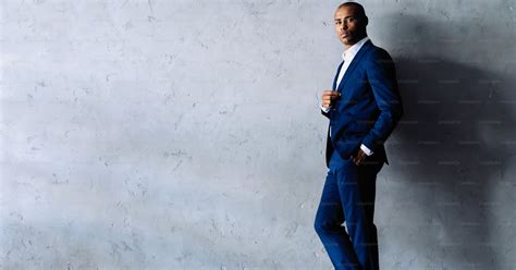 검은 양복을 입은 웃는 사업가가 카메라를 보고 회색 배경에 고립되어 서 있다 사진 Unsplash의 양복 이미지