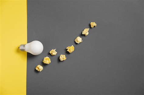 검은 색과 노란색 배경에 구겨진 사무실 용지와 흰색 전구와 새로운 아이디어 개념 브레인 스토밍 세션 동안 창조적 인 솔루션 플랫 레이 상단 보기 복사 공간 개념에 대한 스톡