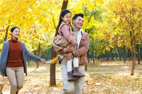 Счастливая молодая семья с двумя детьми гуляет вместе в осеннем лесу