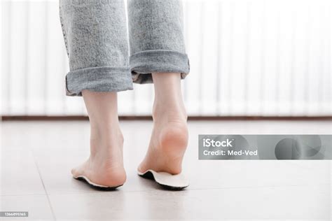 실내에서 정형 외과 깔창을 피팅 여성 가까이 집에서 발 옆에 깔창을 들고 있는 소녀 정형 외과 깔창 풋 케어 배너 플랫 피트 보정 발 질환의 치료 및 예방 개선에 대한 스톡