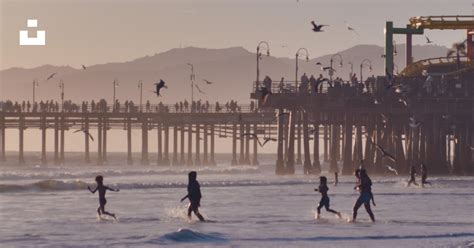 부두 옆 해변을 따라 걷는 한 무리의 사람들 사진 Unsplash의 무료 이미지