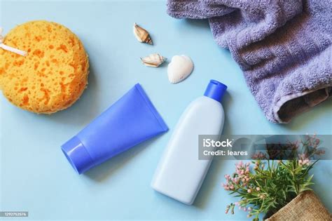 노란색 스폰지 보습 페이스 크림 샴푸 병 테리 타월과 꽃은 파란색 배경에 플랫 레이 천연 스파 화장품 목욕 용품 0명에 대한
