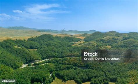 멀리 풍력 터빈이 있는 구불구불한 푸른 언덕의 그림 같은 전망은 자연 경관과 조화롭게 조화를 이루는 재생 에너지를 보여줍니다 0