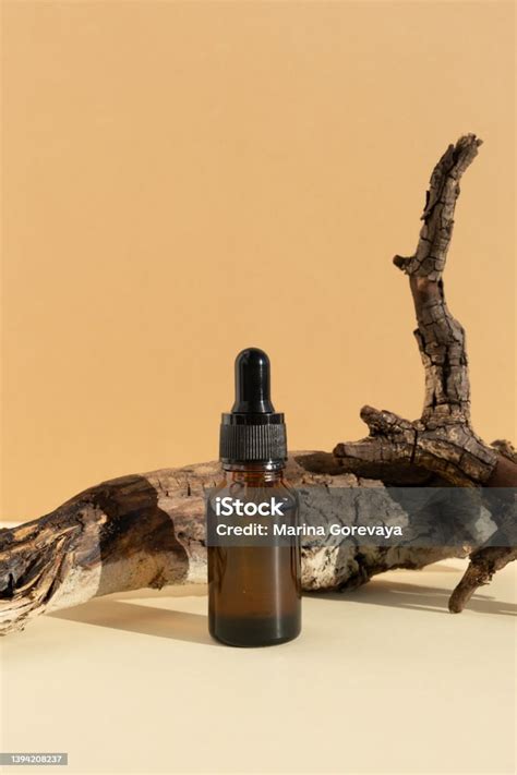 히알루 론산이 든 진한 호박색 유리 병 또는 베이지 색 배경의 마른 가지 근처의 얼굴 혈청 유기 성분을 가진 개념 천연 화장품 디자인의 공간을 복사합니다 정면보기 피부에