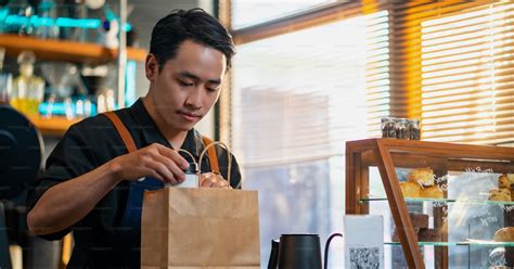 카페에서 일하는 아시아 남자 웨이터 또는 바리 스타의 자신감 테이크 아웃 준비를 하는 남성 커피숍 주인은 바 카운터에서